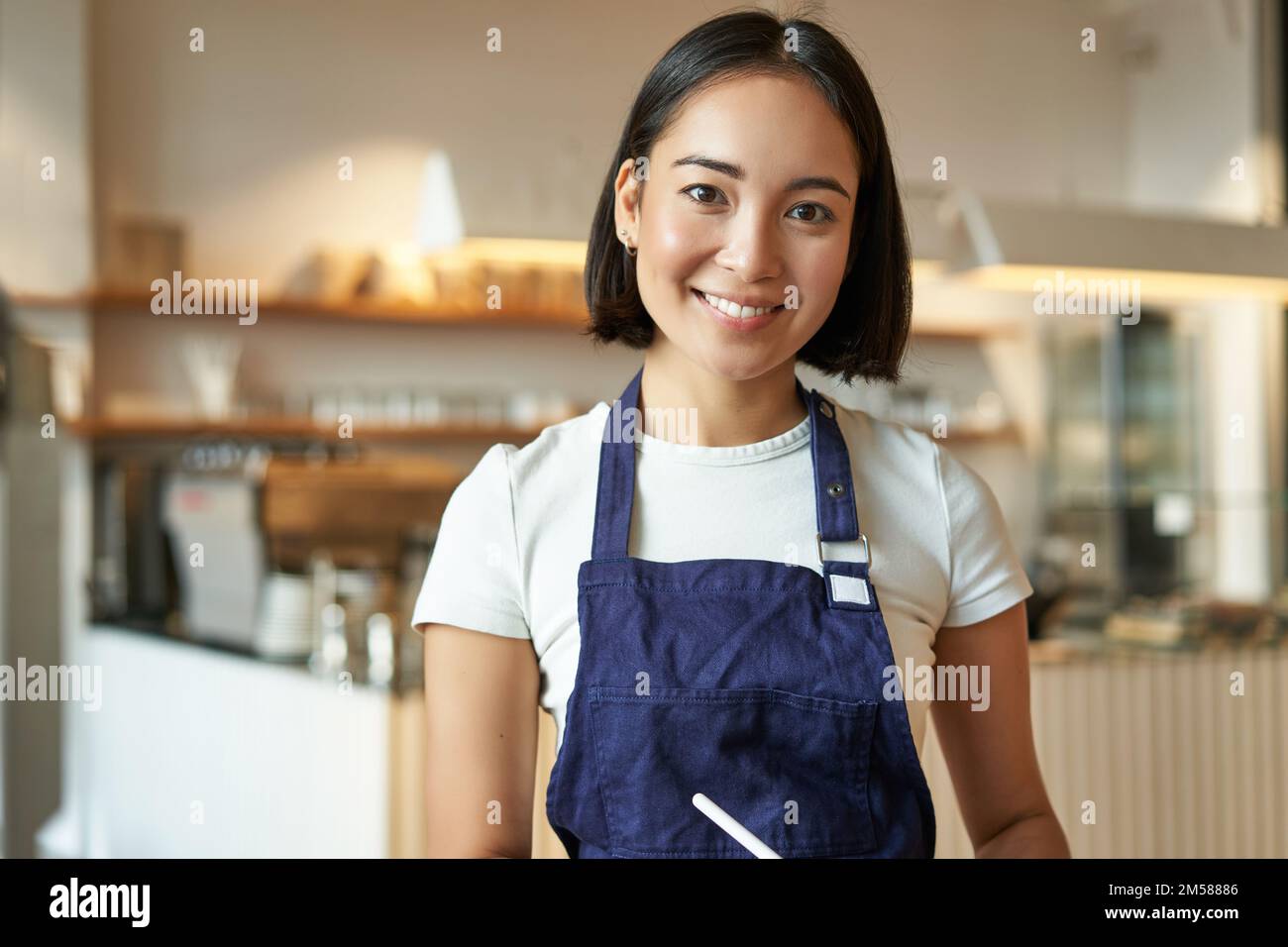 Smiling girl barista, cafe waitress with tablet an pen takes order near ...