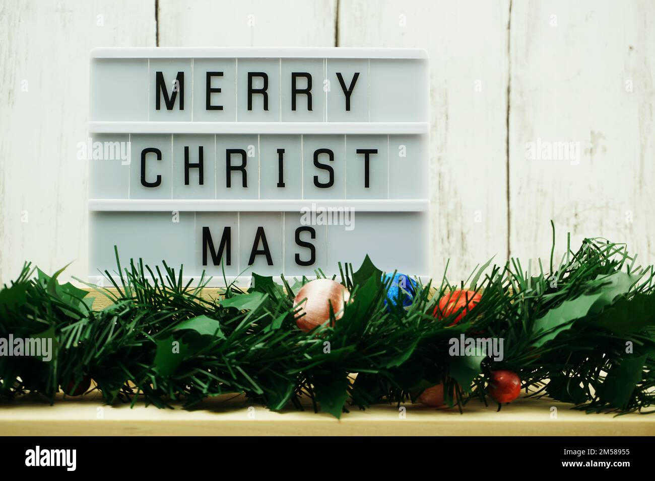 merry Christmas word on light box with green tinsel decoration Stock ...