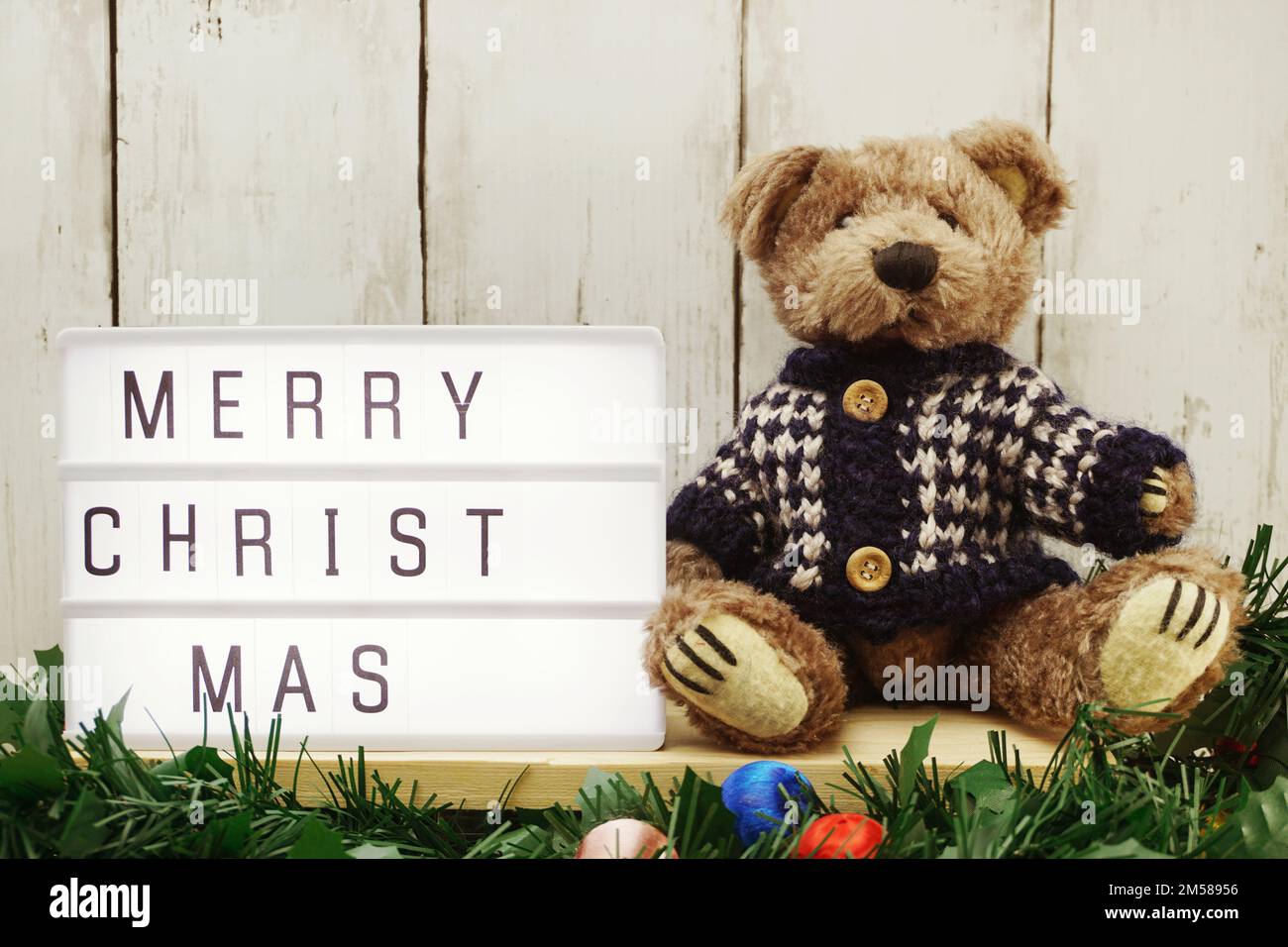 merry Christmas word on light box with teddy bear and green tinsel ...