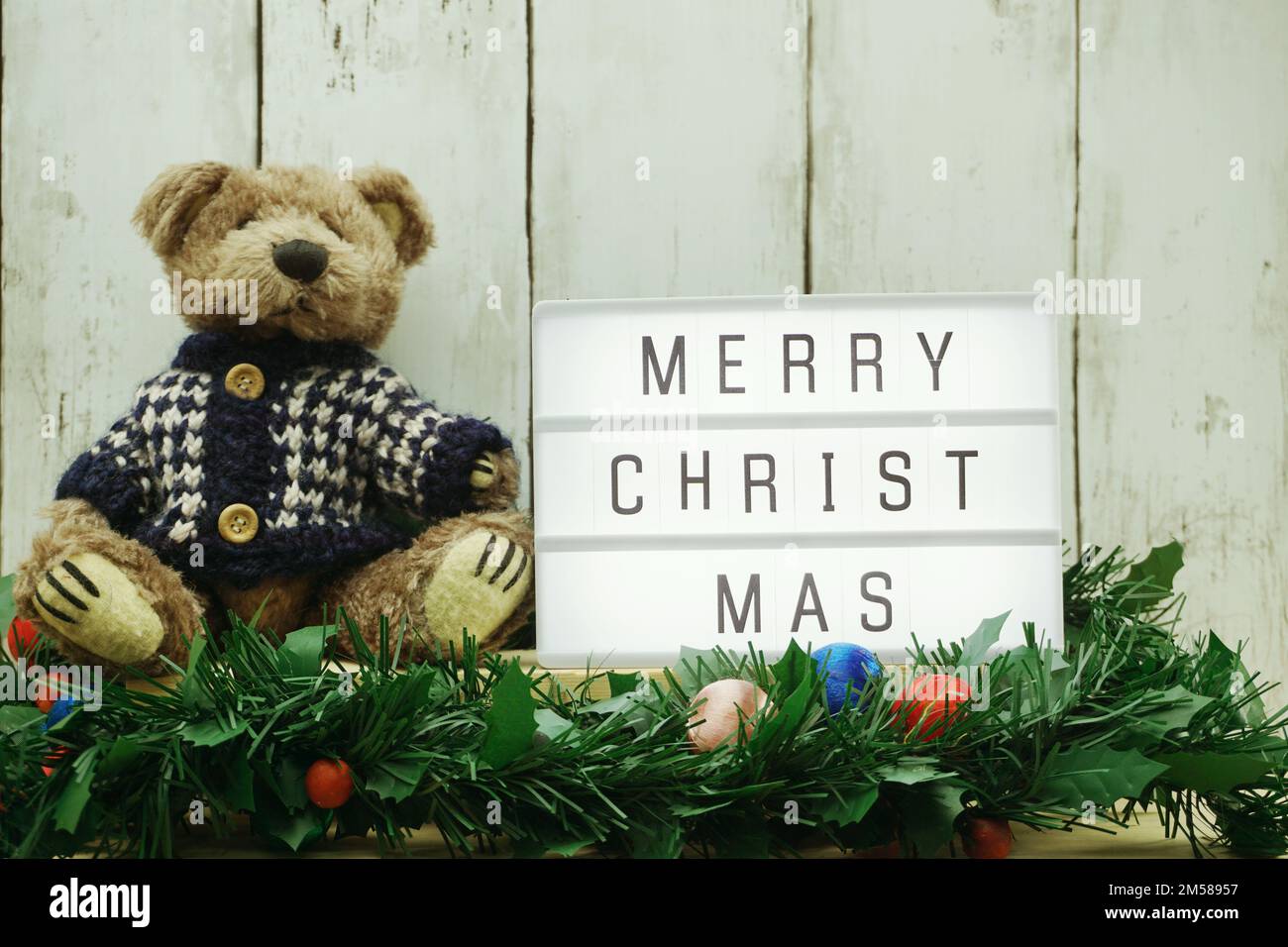 merry Christmas word on light box with teddy bear and green tinsel ...