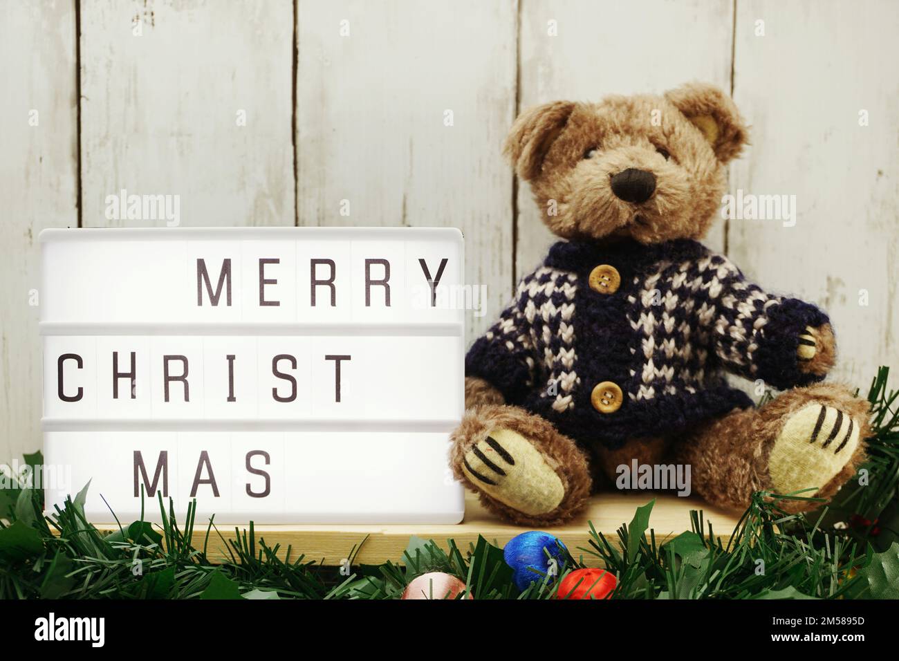 merry Christmas word on light box with teddy bear and green tinsel ...