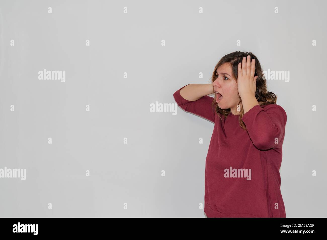 woman on a white background surprised with her hands on her head ...