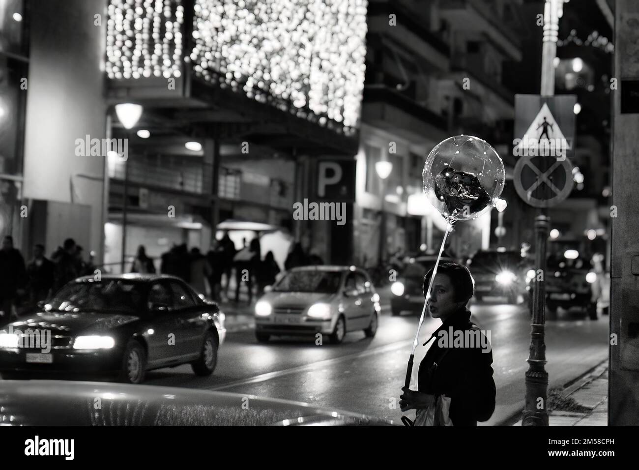 Woman holding festive balloon on city street at night Stock Photo - Alamy