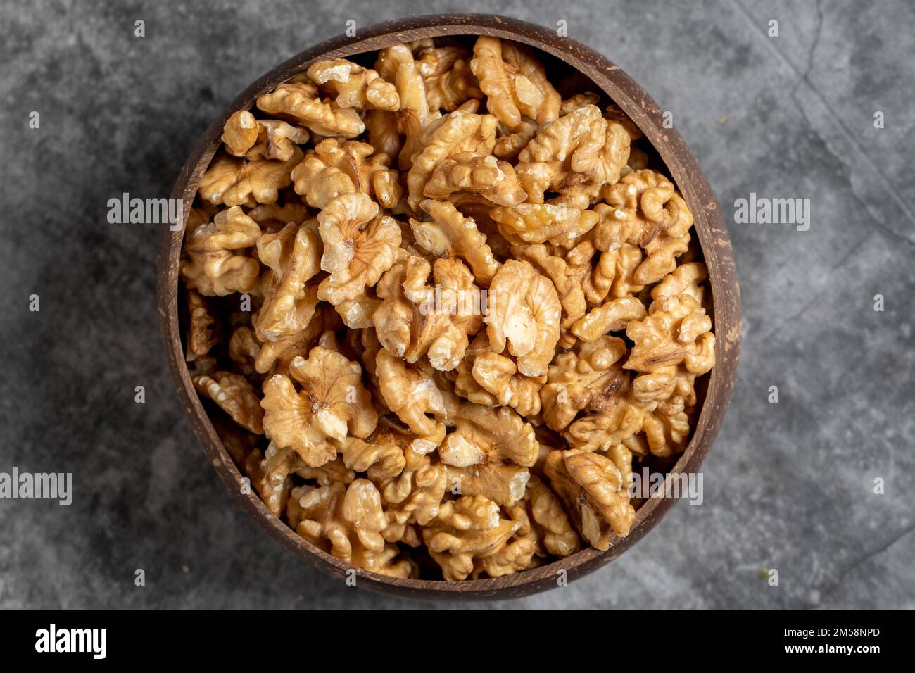 Walnuts in a bowl on a dark background. Walnuts in a coconut bowl. Top ...