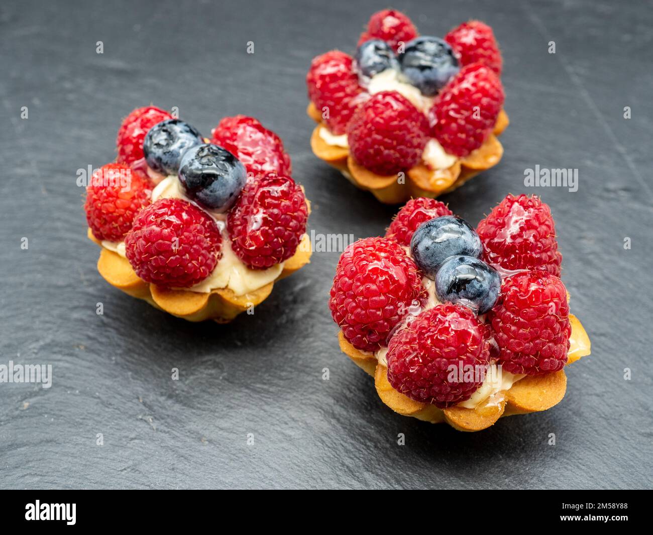 raspberry and blackberry tart on black slate Stock Photo - Alamy