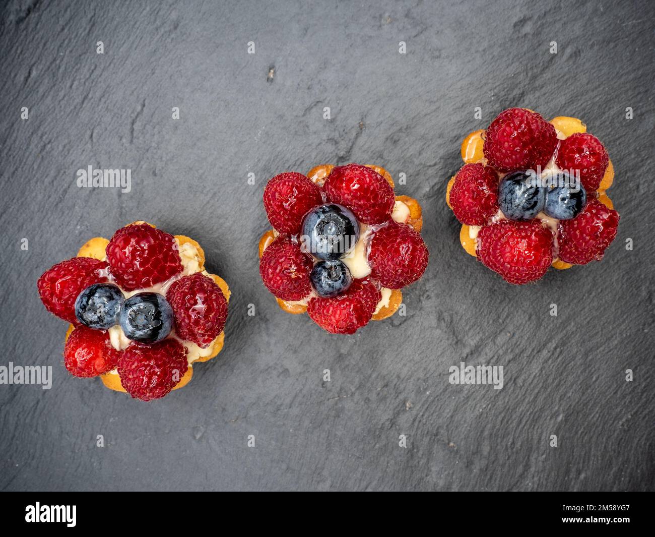 raspberry and blackberry tart on black slate Stock Photo - Alamy