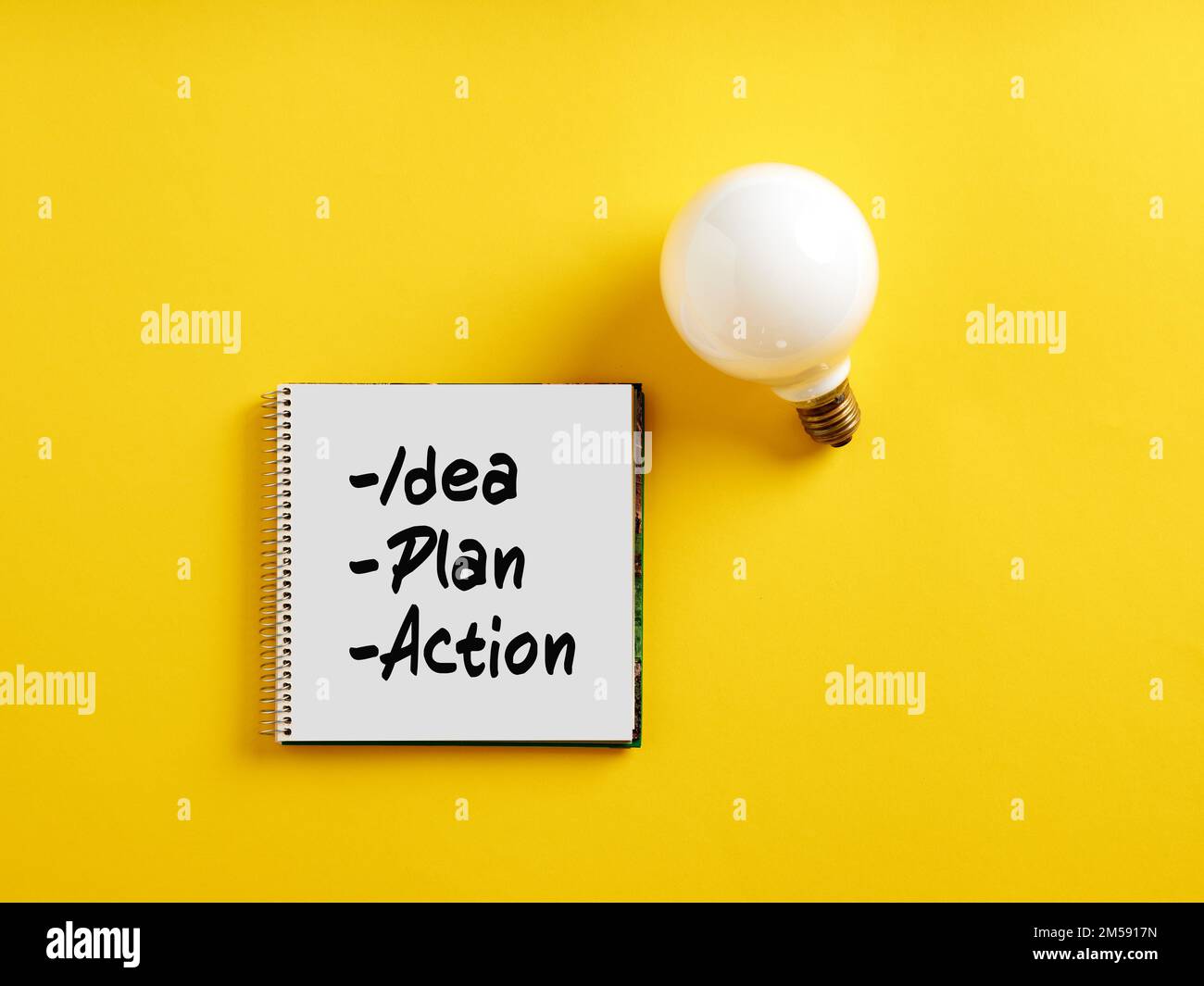 The words idea, plan, and action on notepad with a light bulb. Business ...