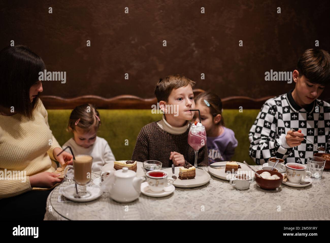 Happy family eating desserts together at cozy cafe and having fun. Boy ...