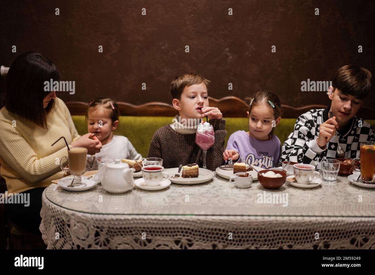 Happy family eating desserts together at cozy cafe and having fun. Boy ...