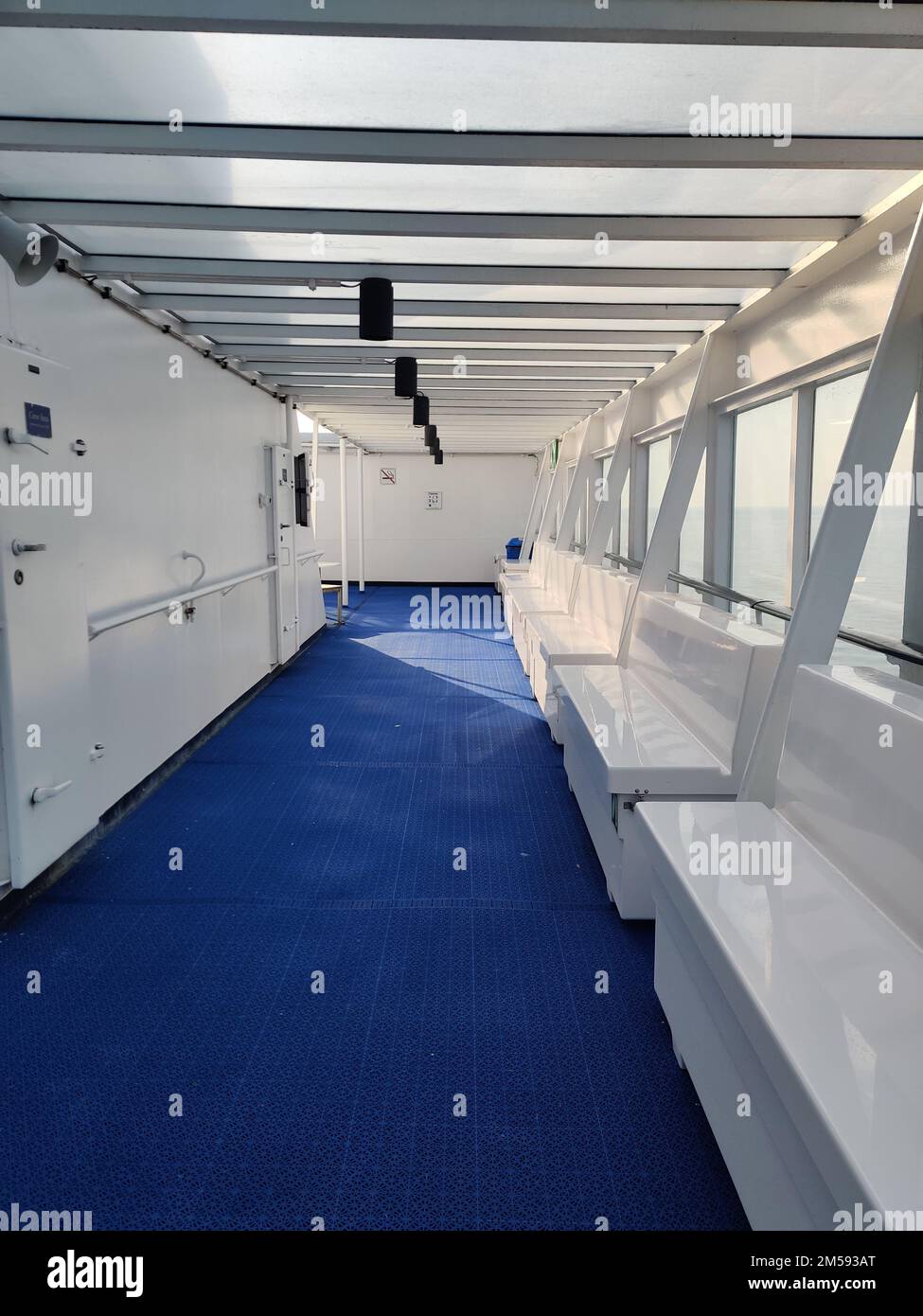 A long row of white benches next to each other in a white ship corridor ...