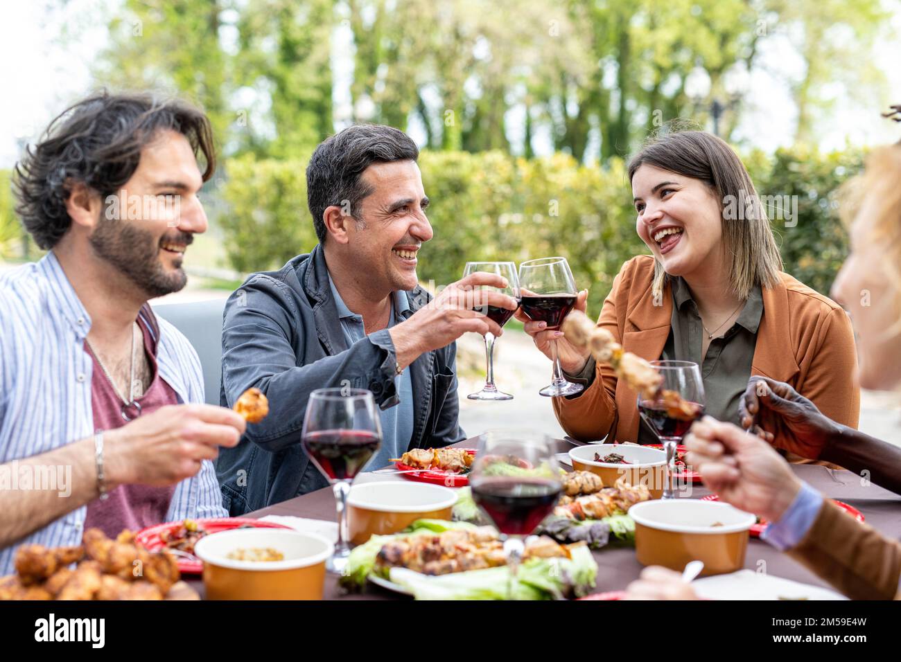Happy family cheering with red wine at barbecue lunch outdoor ...