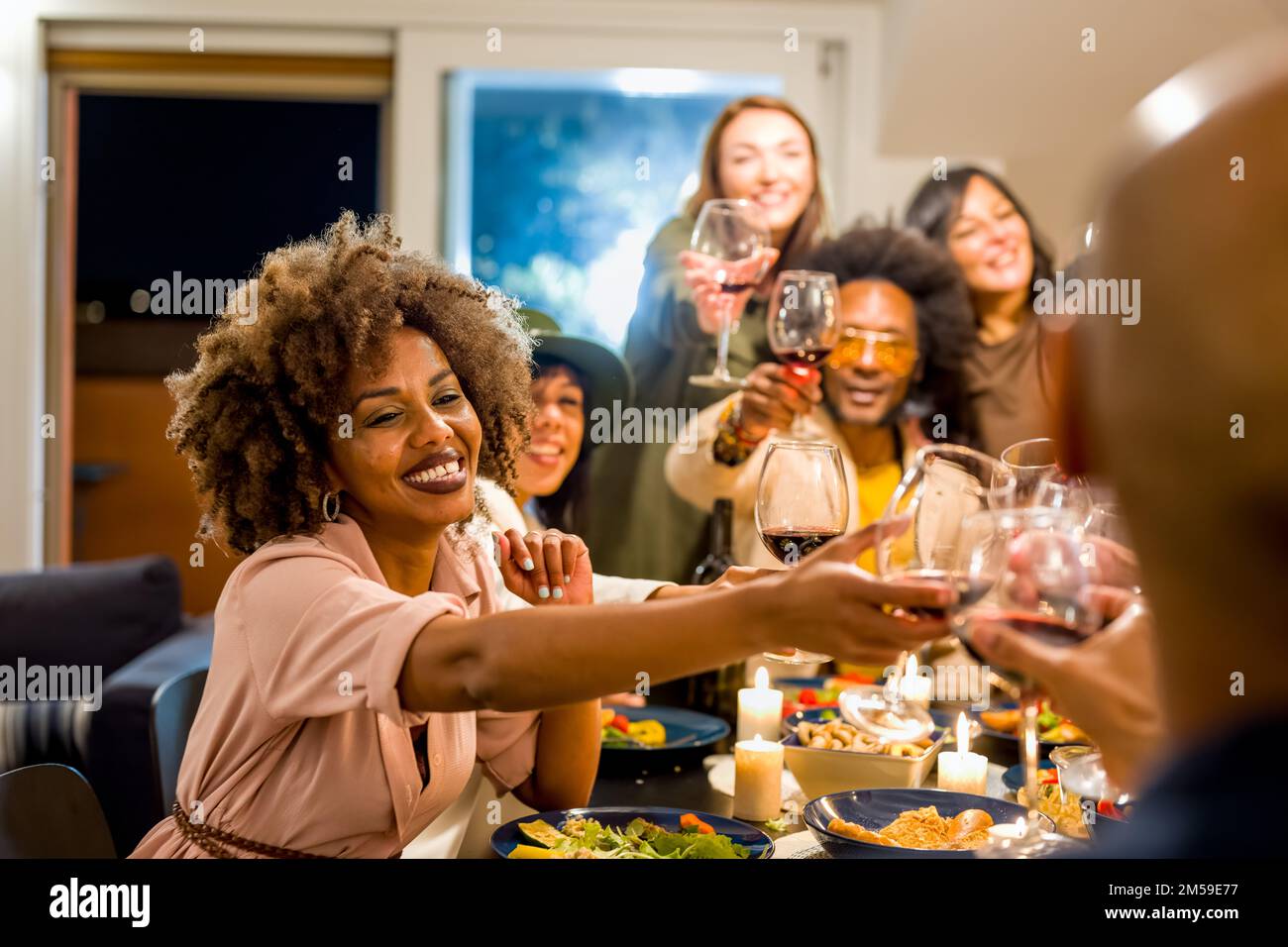 Mixed age range group of friends toasting at dinner party, focus on ...