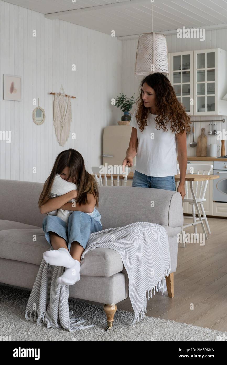 Frightened crying teenage girl sits on sofa hugging pillow and is ...