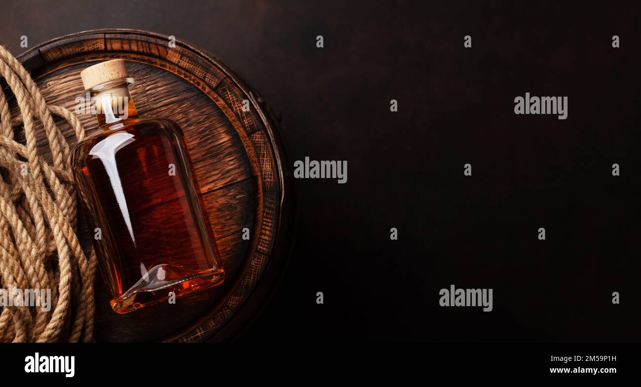 Bottle with rum, cognac or whiskey. Over old wooden barrel. Top view ...