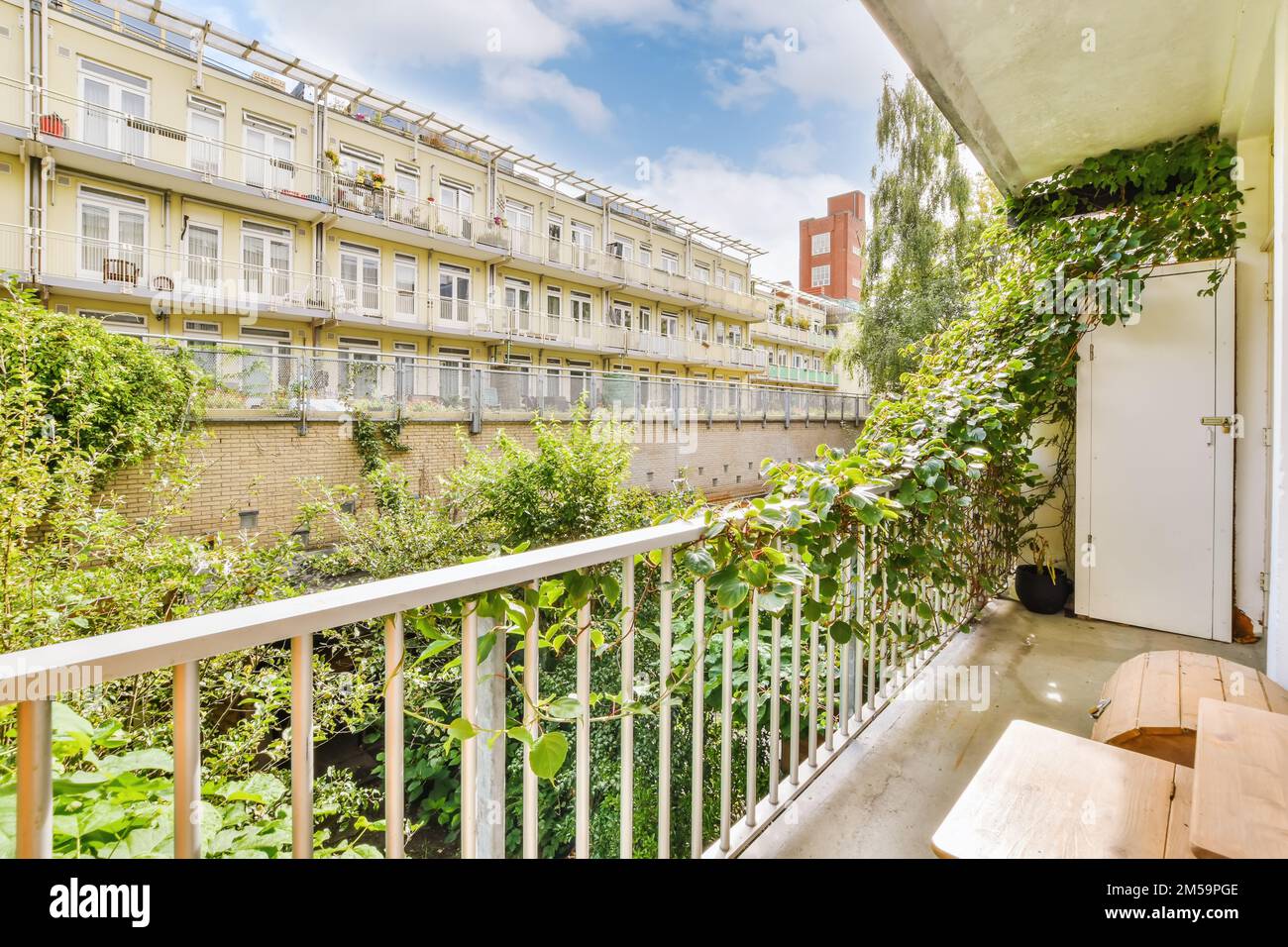 a balcony with plants growing on the wall and wooden bench in front of ...