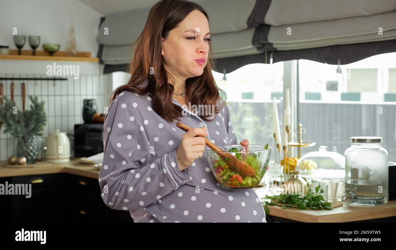 Pregnant woman stirs and eats healthy salad with vegetables Stock Photo ...