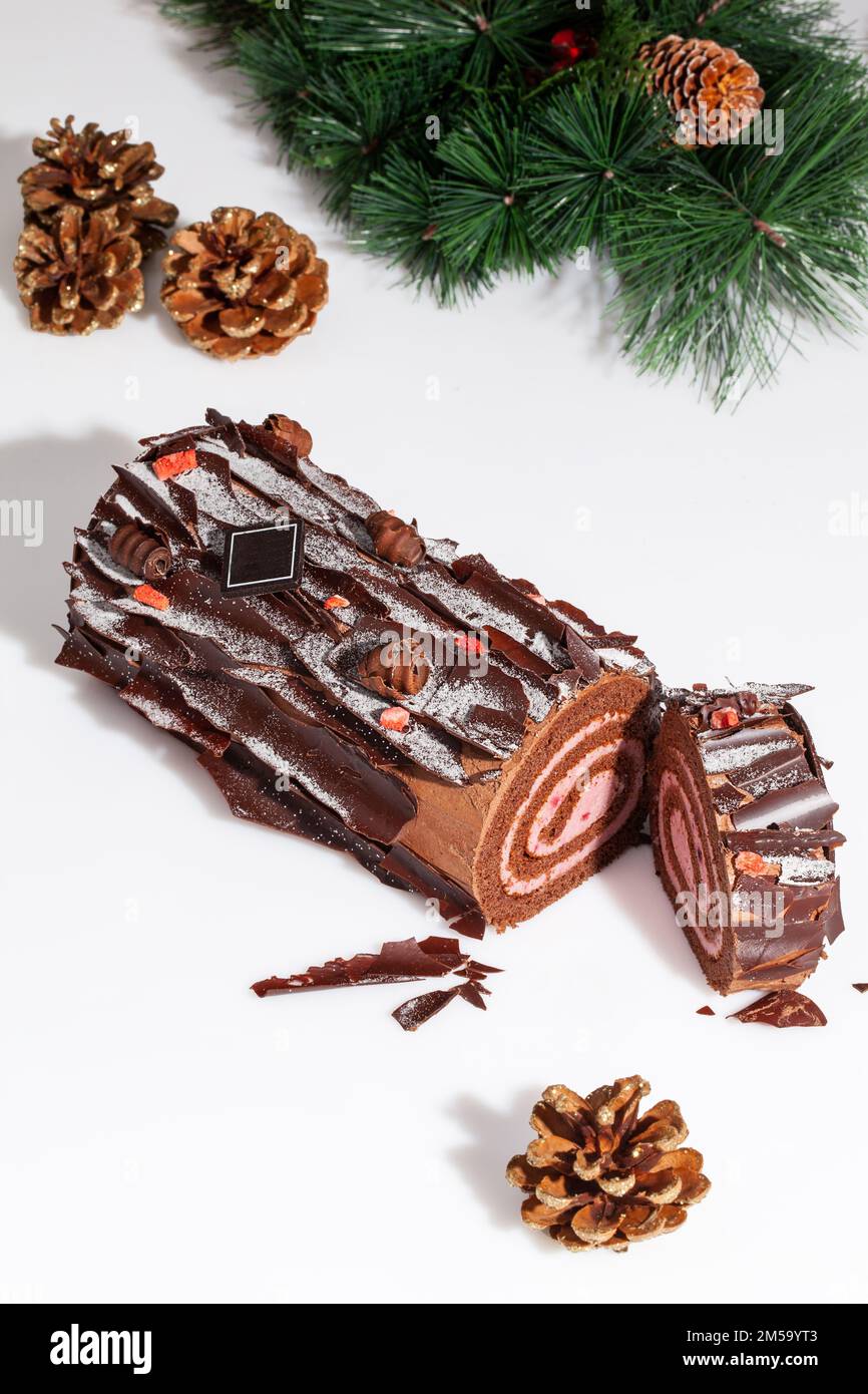 Sliced chocolate roll on white background with pine branch and fir ...