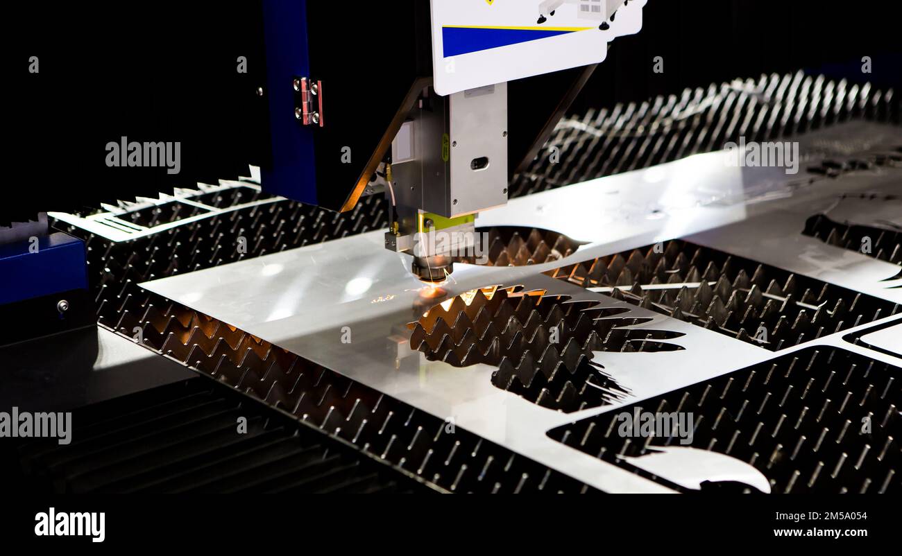 CNC laser cutting machine cutting metal sheet in factory. Industrial ...