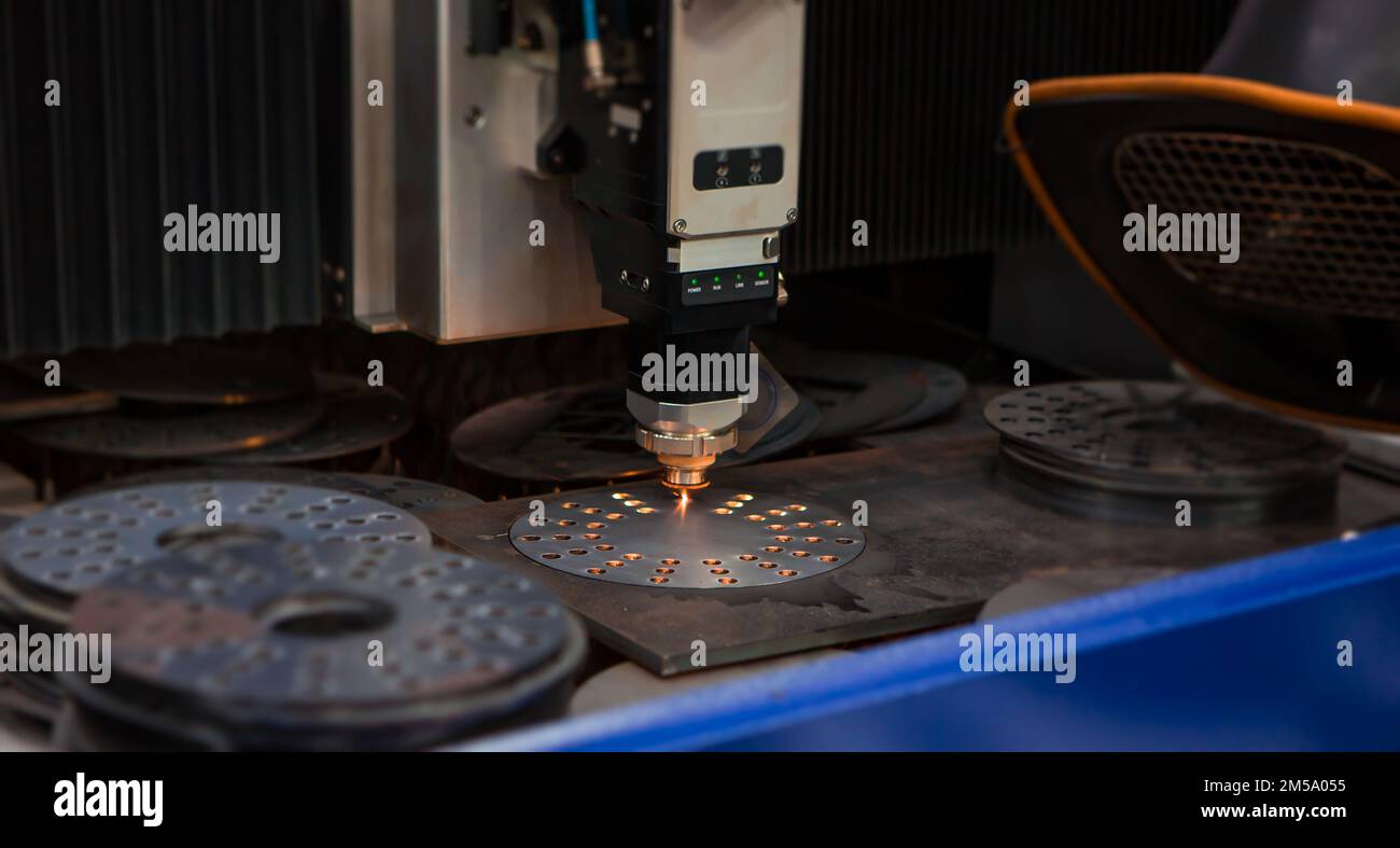 CNC laser cutting machine cutting holes on metal workpiece in factory ...