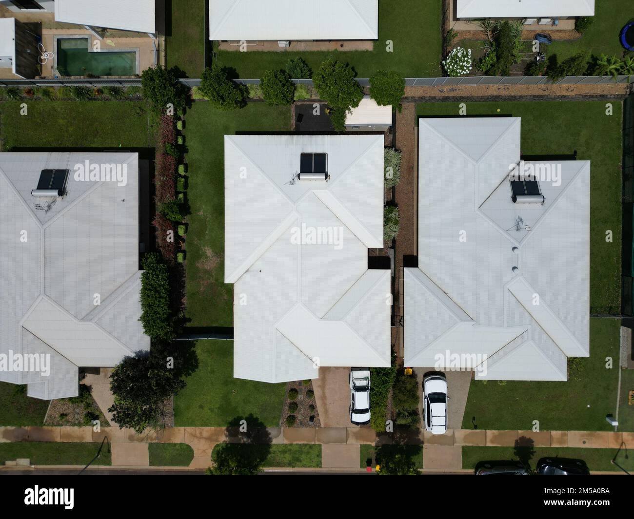 A top view of a residential area with cars and houses with white roofs ...