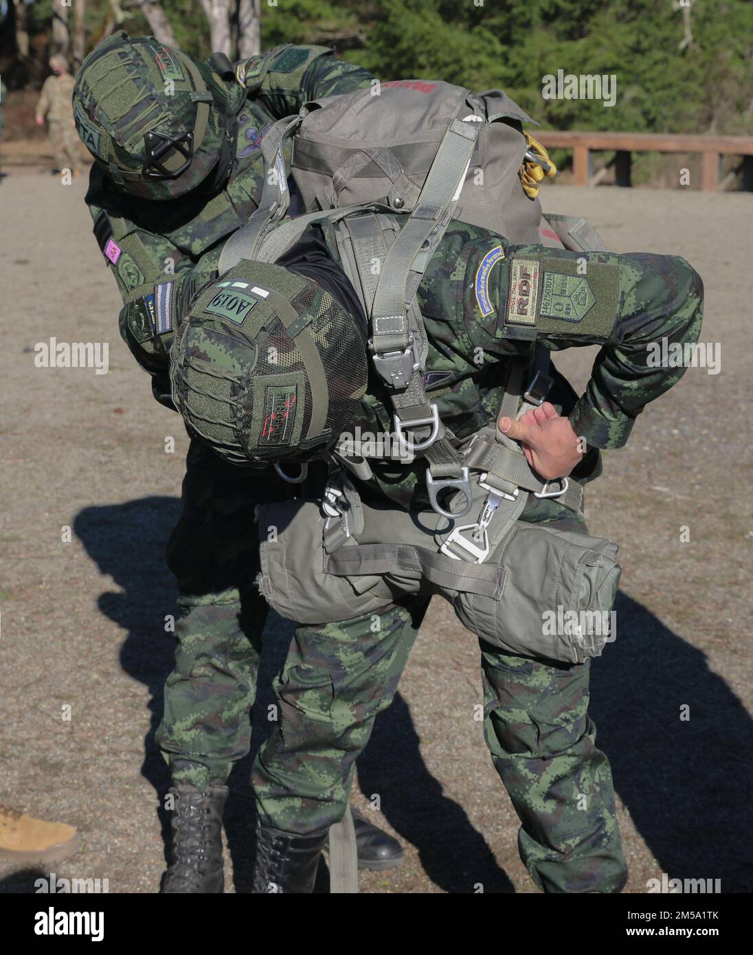 A Royal Thai Army Paratrooper assists another in rigging a T-11 ...