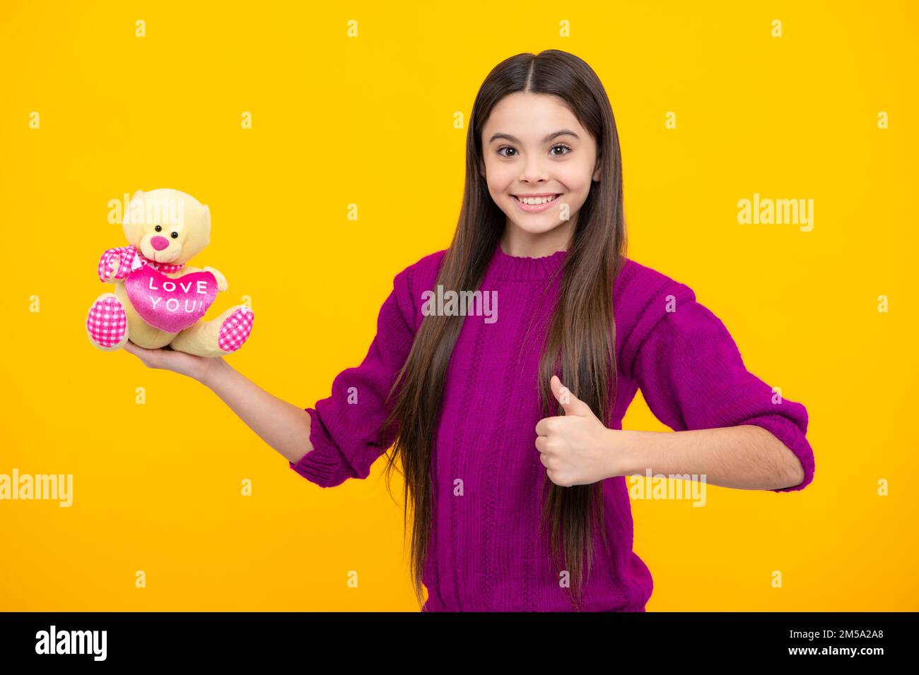Teen girl child in casual wear holding plush toy isolated on yellow ...