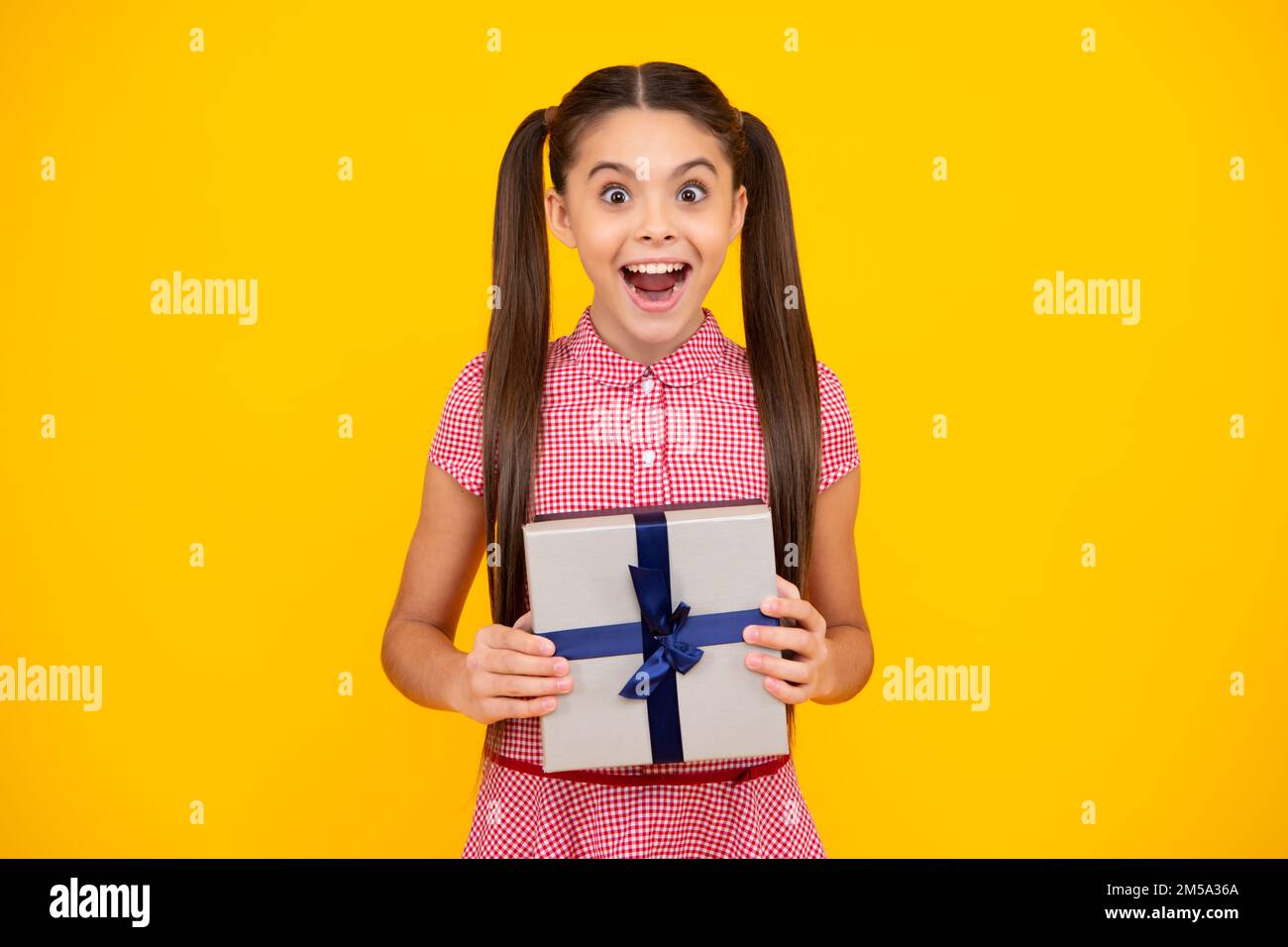 Amazed teenager. Child with gift present box on isolated studio ...
