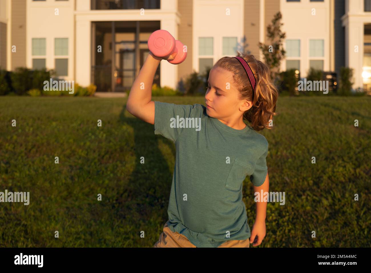 Cute child boy pumping up arm muscles with dumbbell. Fitness kids with ...