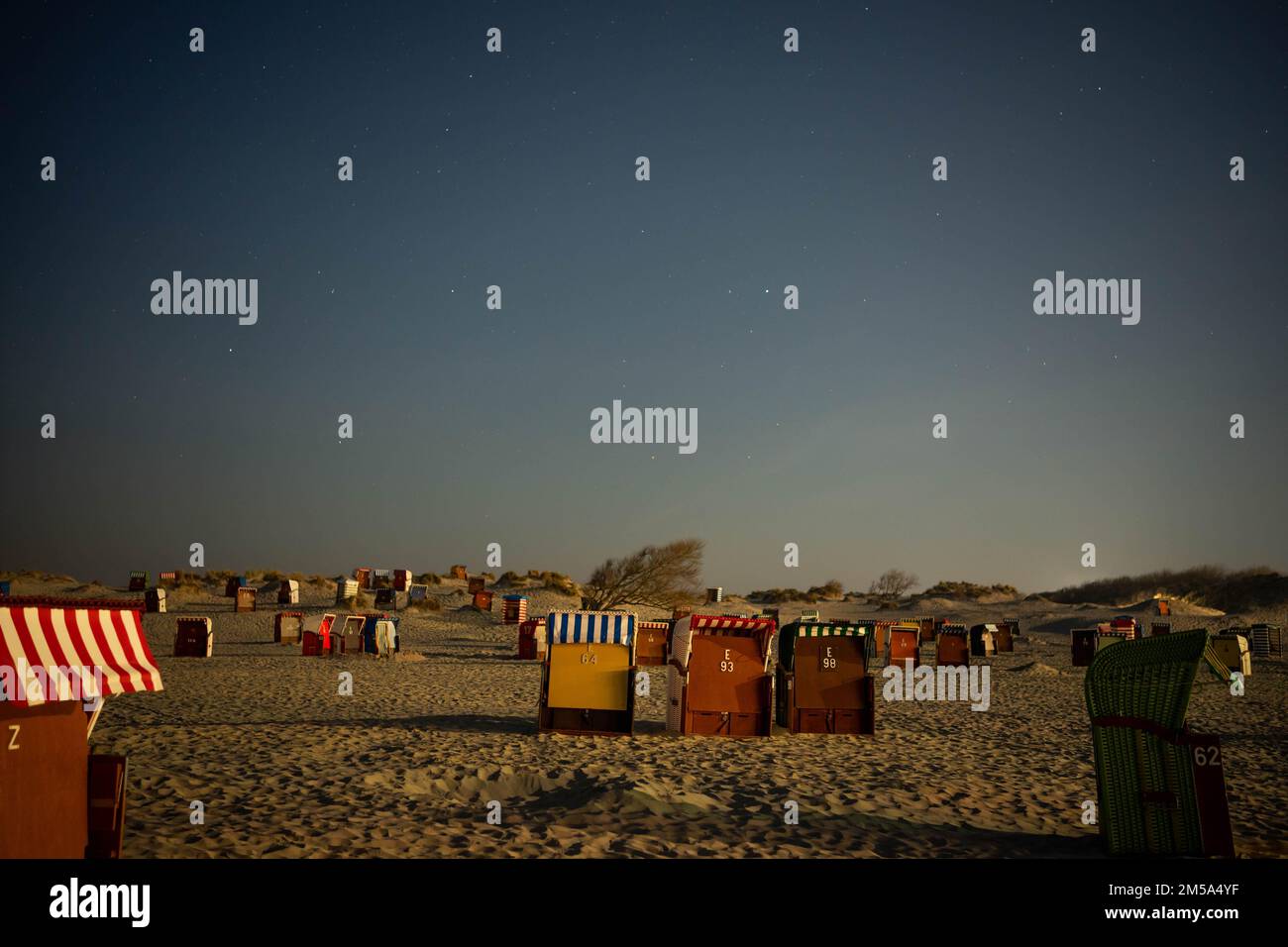 Multiple closed beach chairs on the sand of a coast under the blue ...