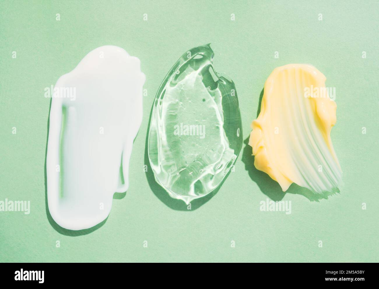 Cream and gel smudges over green background, various cosmetic products ...