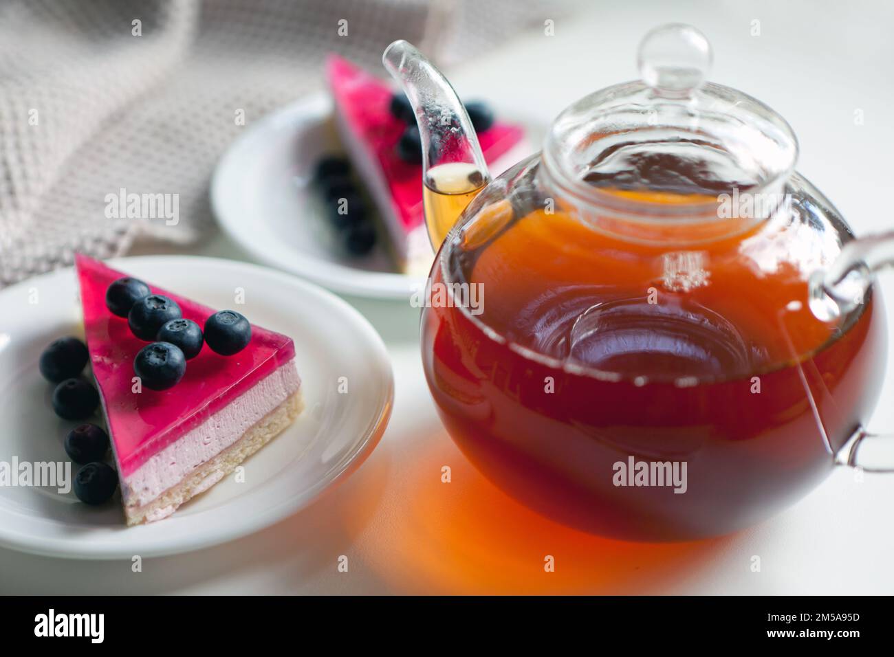 teapot with hot black tea and cake on plate with berries. afternoon tea ...