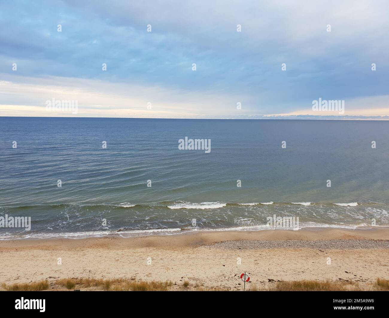 The calm foamy waves of the ocean meeting the sandy shore with the ...