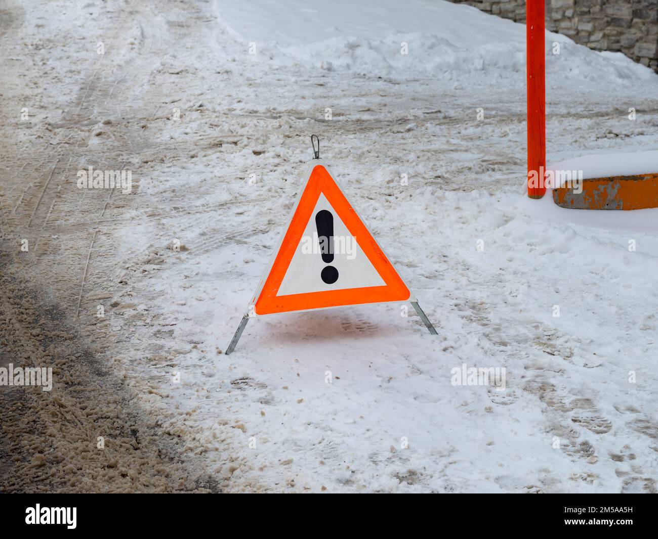 Warning triangle in the dirty snow on a winter street. Symbol for an ...