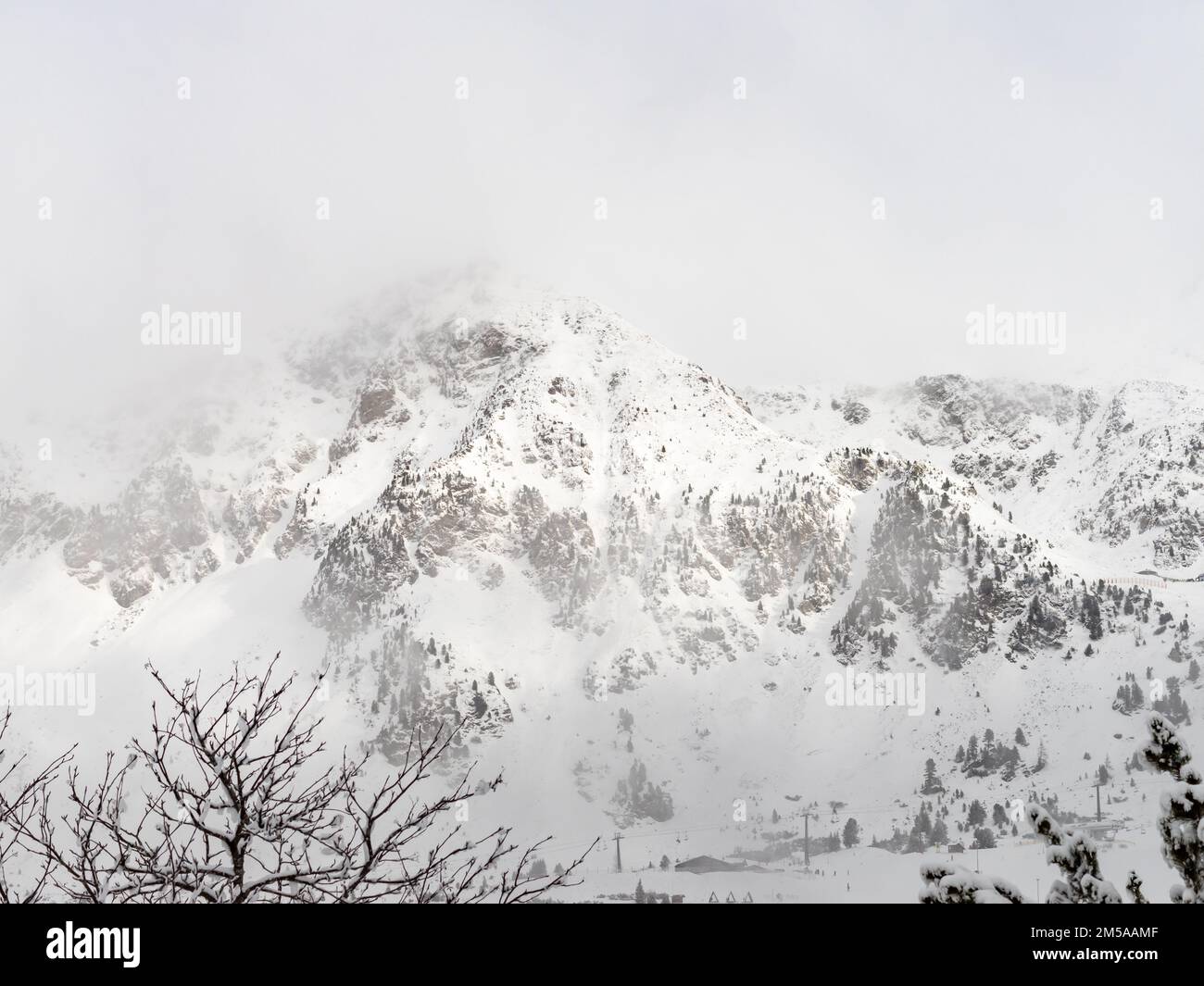 Huge snowy mountain behind a big white cloud. Ski resort in the ...