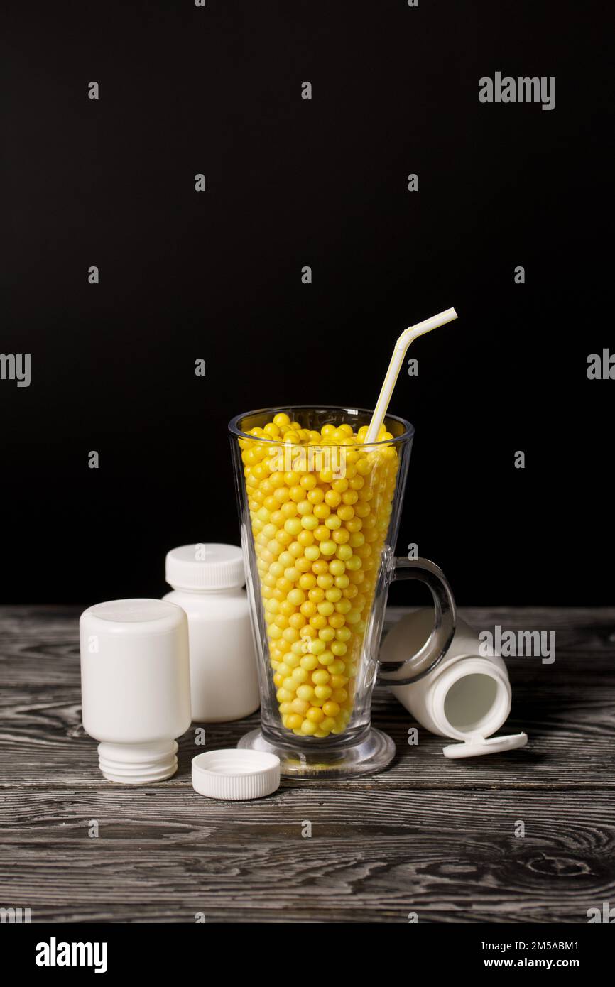 The glass goblet is filled with vitamins in the form of dragees. Near ...