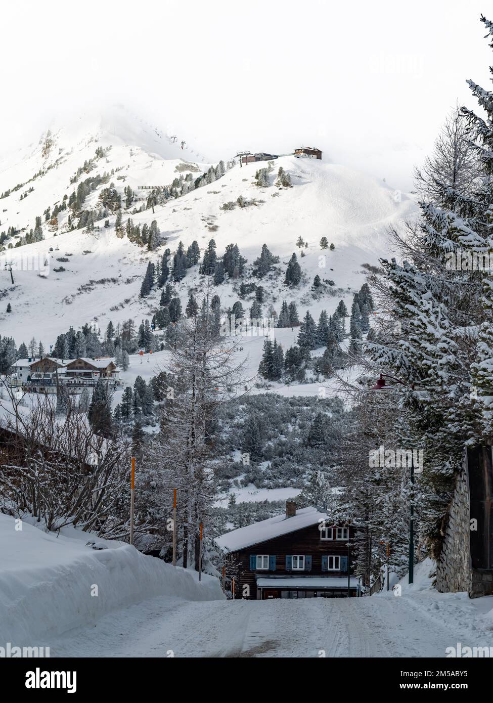 Street view in the European Alps with a wooden house at the end of the ...
