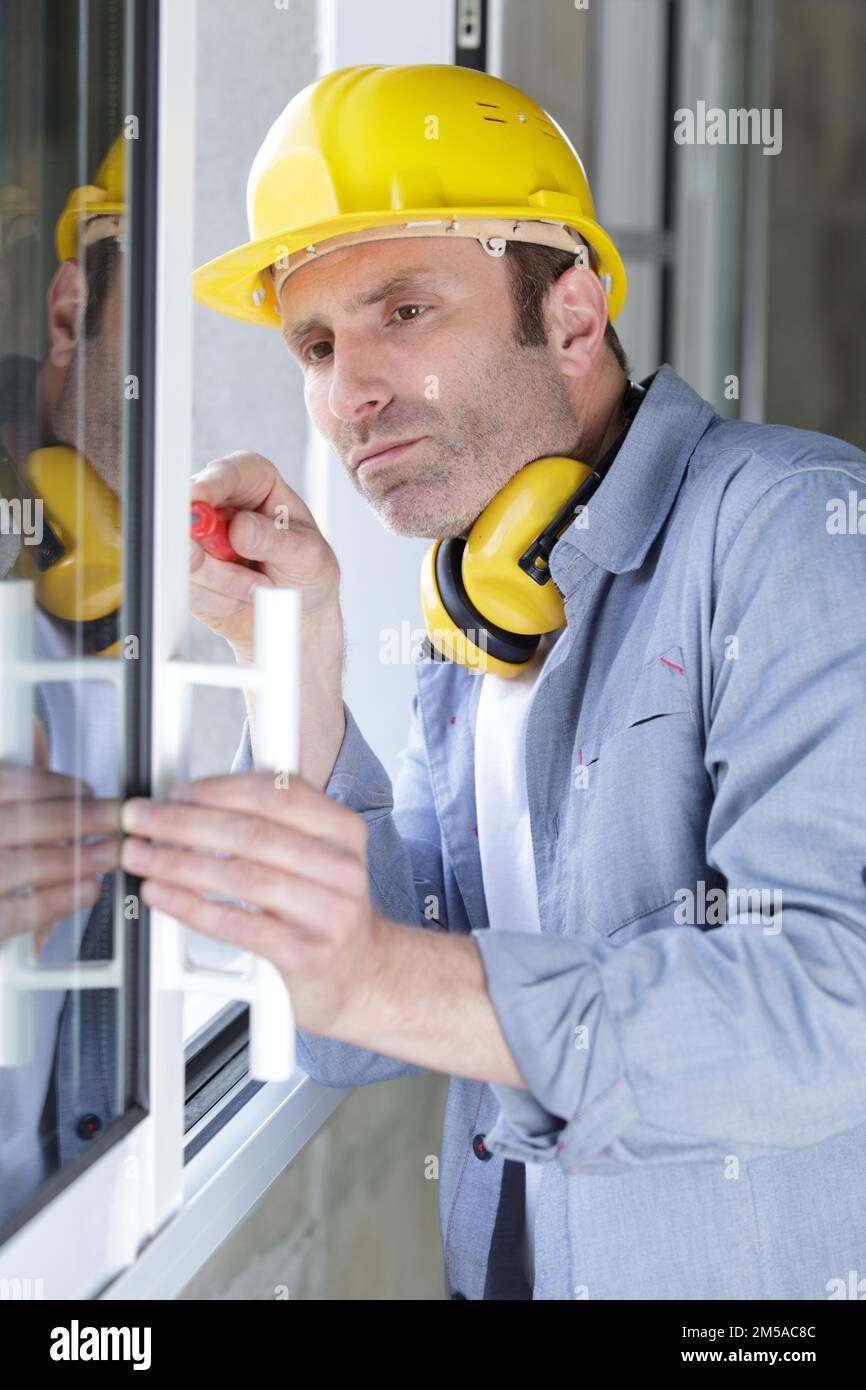 workman making adjustment to window handle Stock Photo - Alamy