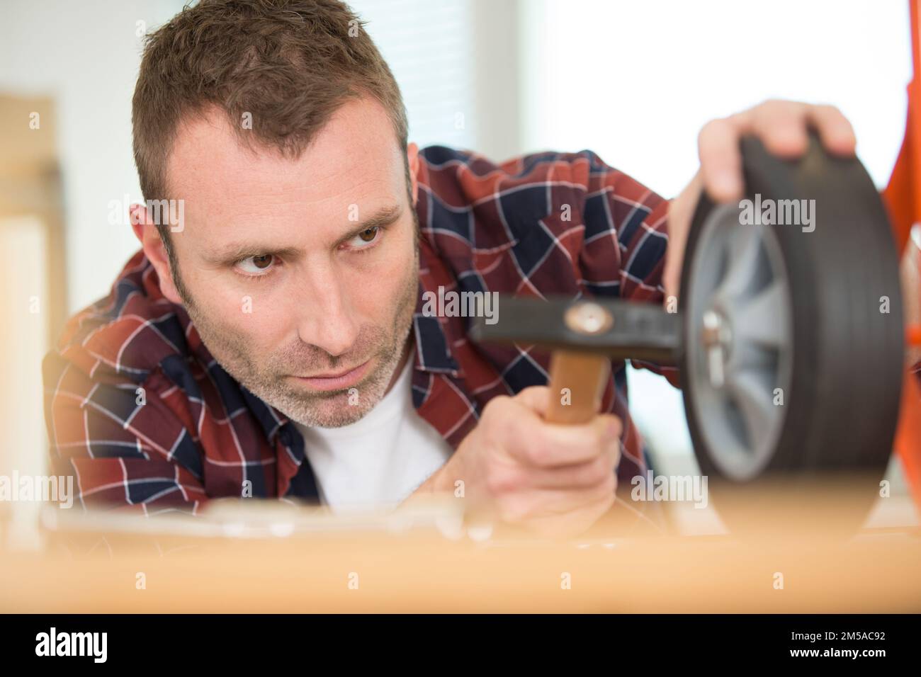 man hammering split pin into trolley wheel Stock Photo - Alamy