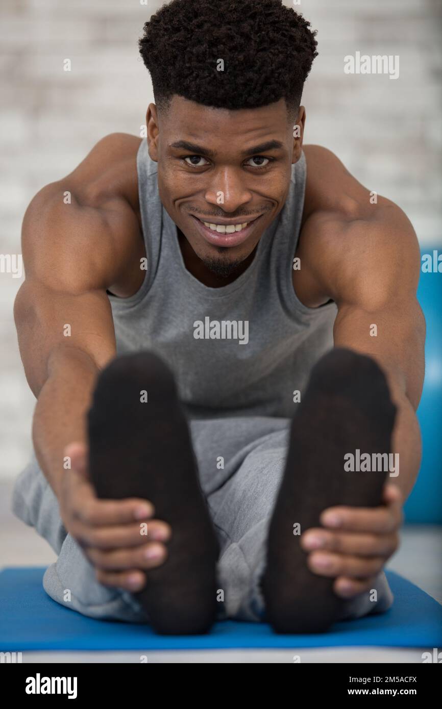 muscular man stretching forward and holding his feet Stock Photo - Alamy