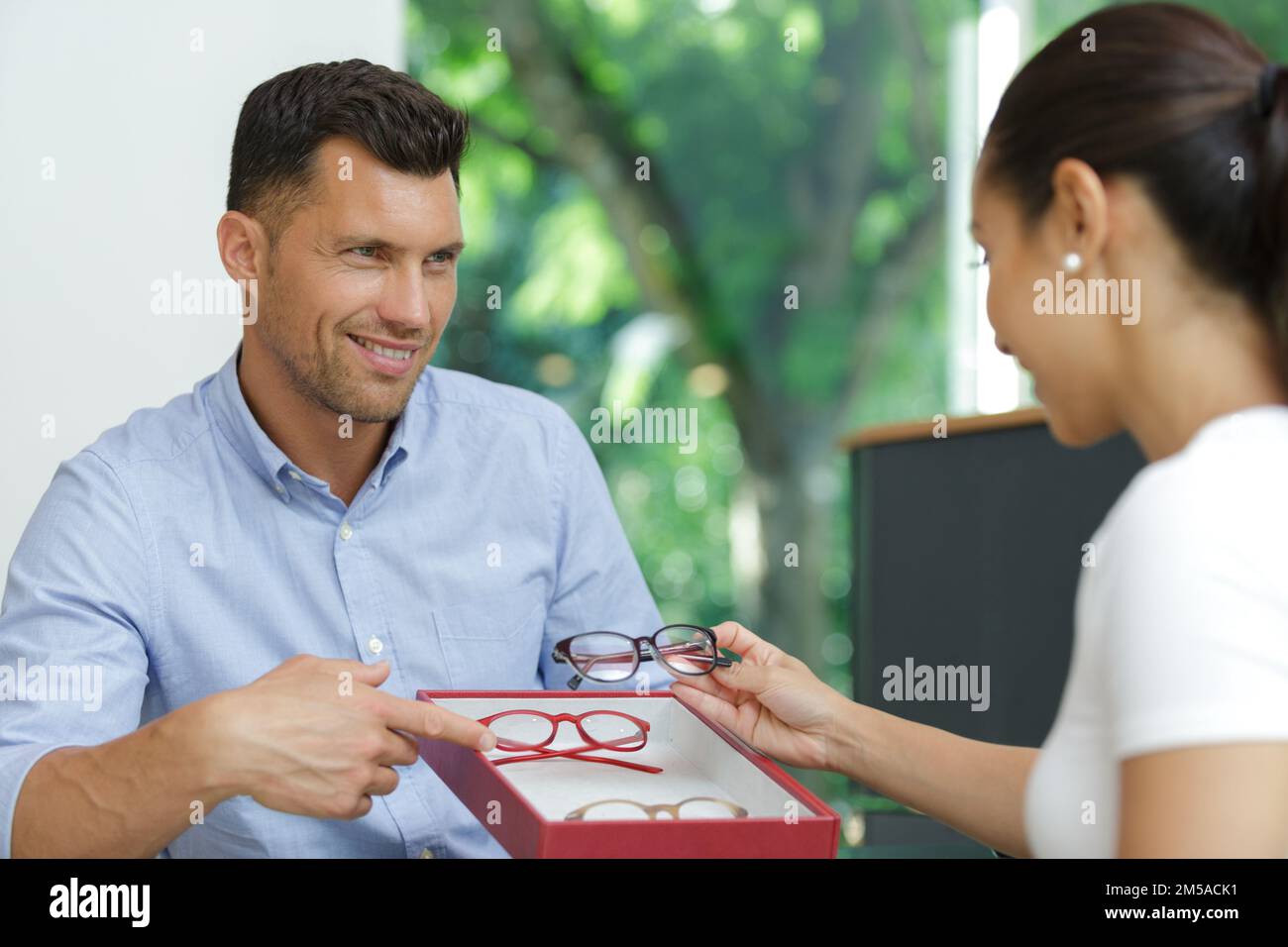 customer considering a selection of eyeglasses to try Stock Photo - Alamy