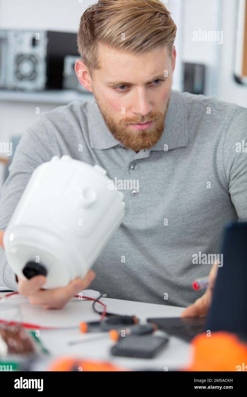 engineer holding parts and using laptop Stock Photo - Alamy