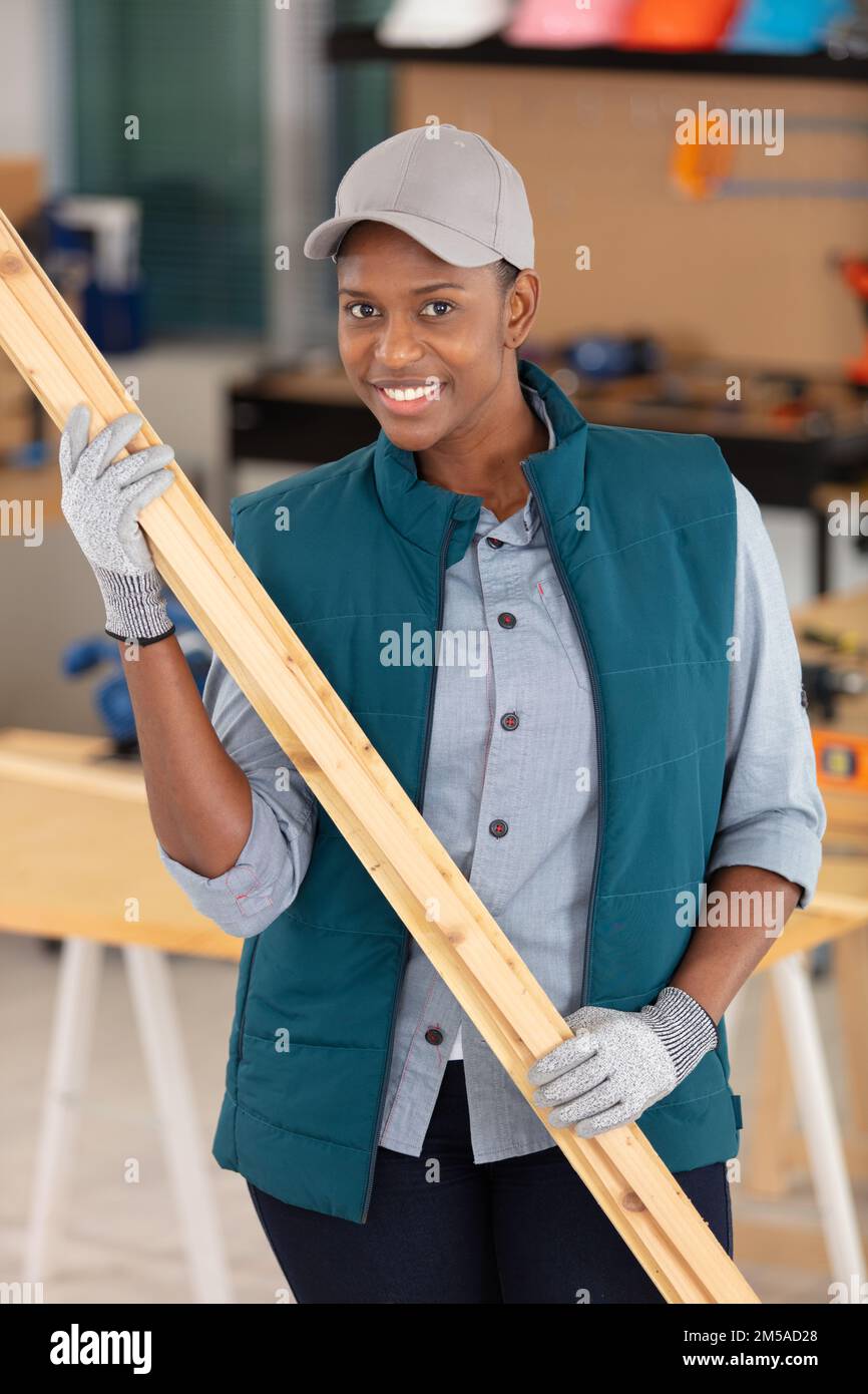 portrait of smiling female carpenter holding length of wood Stock Photo ...