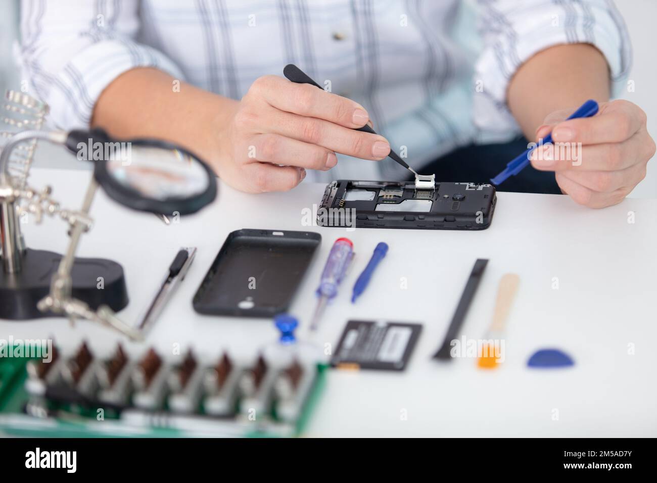 technician repairs a smartphone with precision tools Stock Photo - Alamy