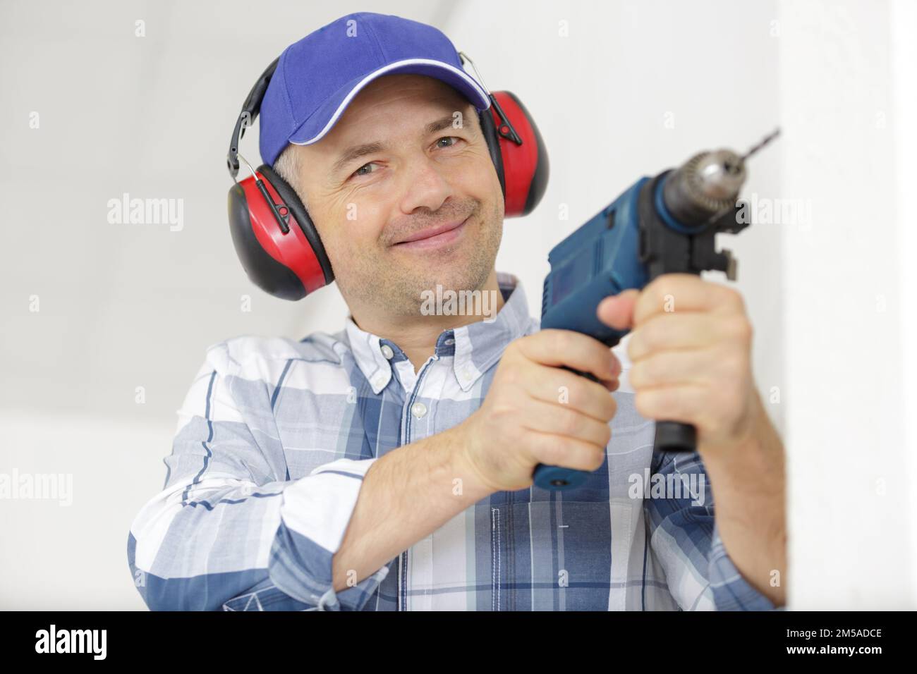 happy male with beard making a hole in white wall Stock Photo - Alamy