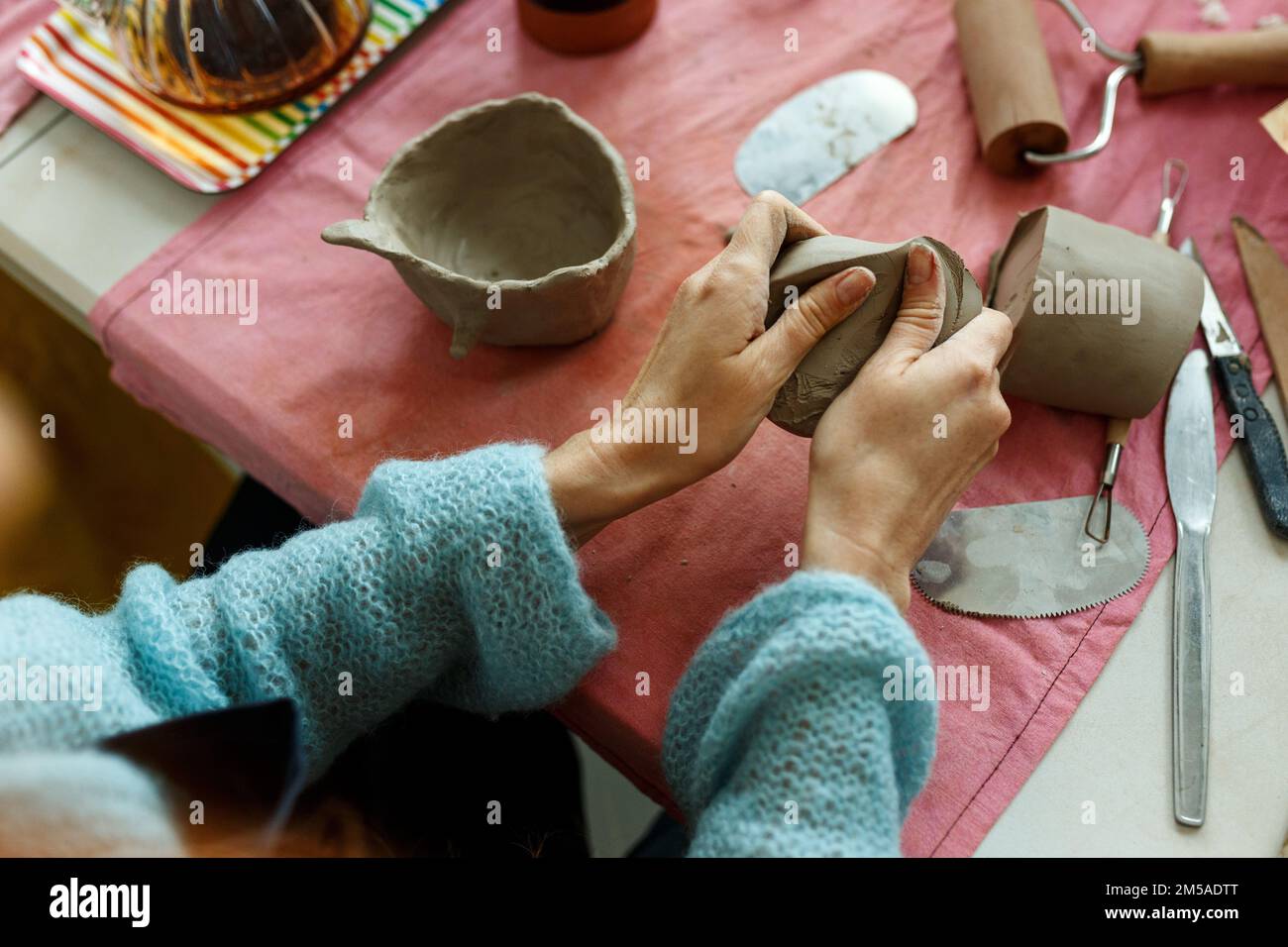 Kneading piece of raw grey clay by female hands on wooden table. DIY ...