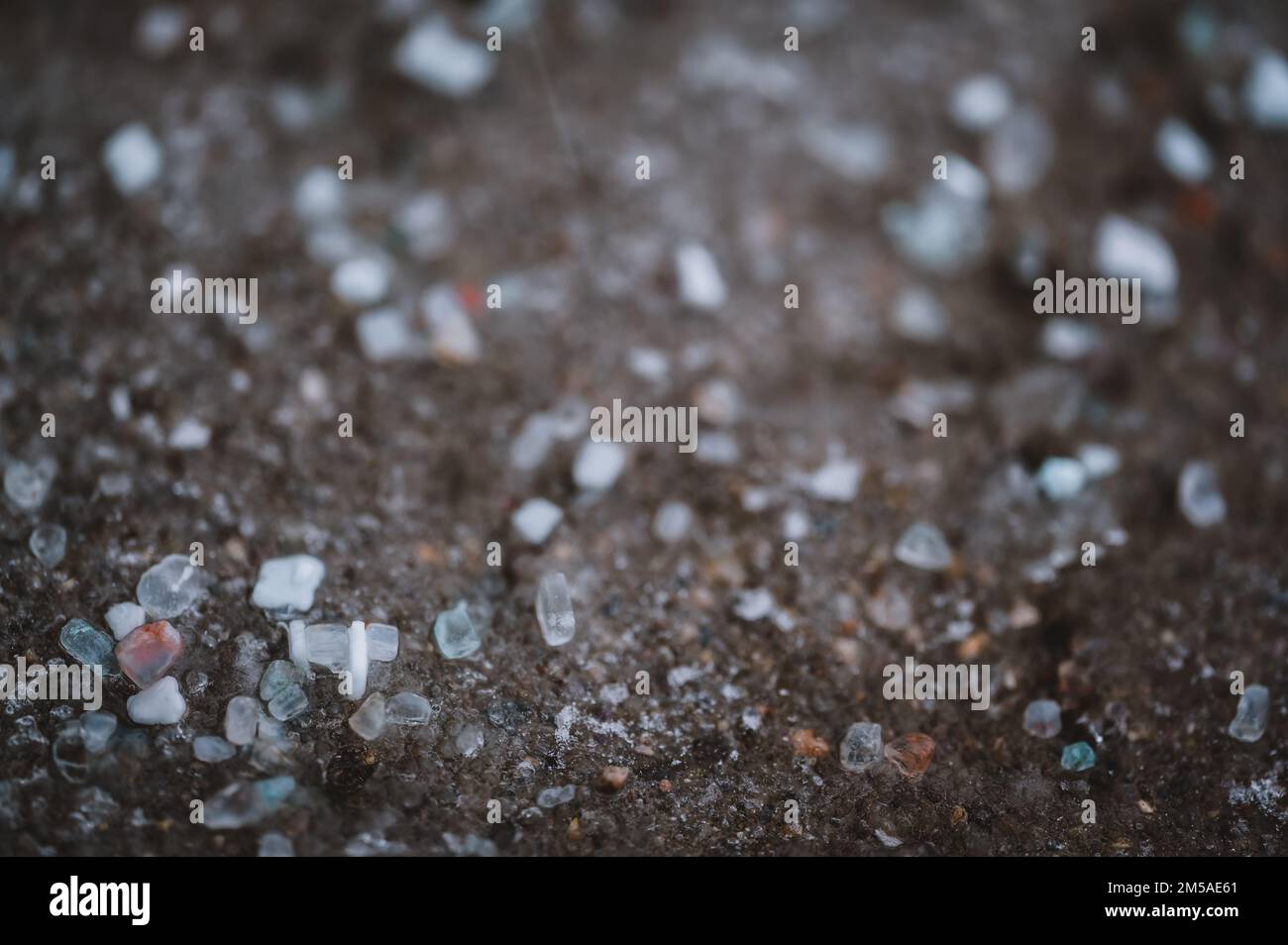 macro ground level closeup view of rock salt ice-melt on concrete with ...