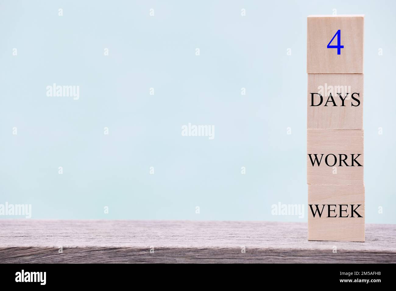 4 day working week words on wooden cube on blue background. reducing ...