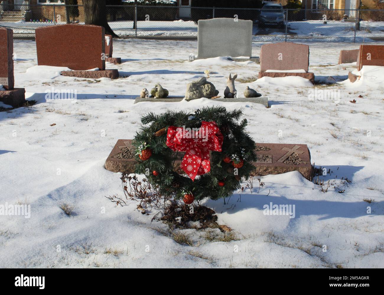 Christmas wreath with large bow in front of a headstone in winter with ...