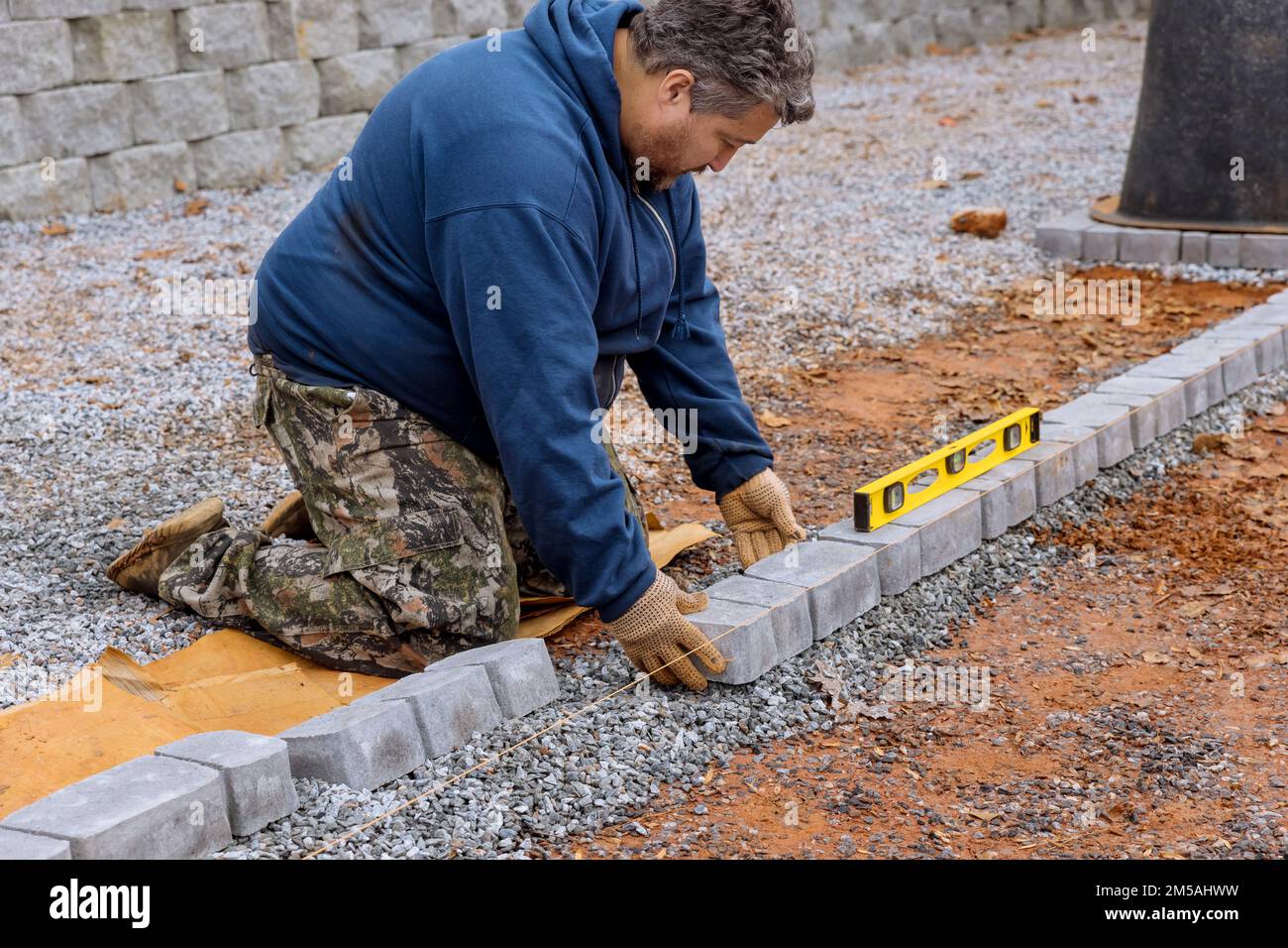 Construction worker installing arranging precast concrete pavers stone ...