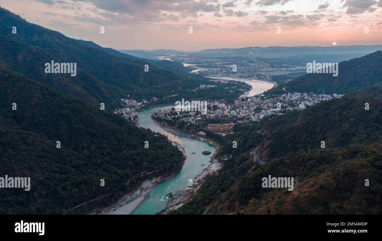 An aerial view of a river along Rishikesh valley and city with forested ...